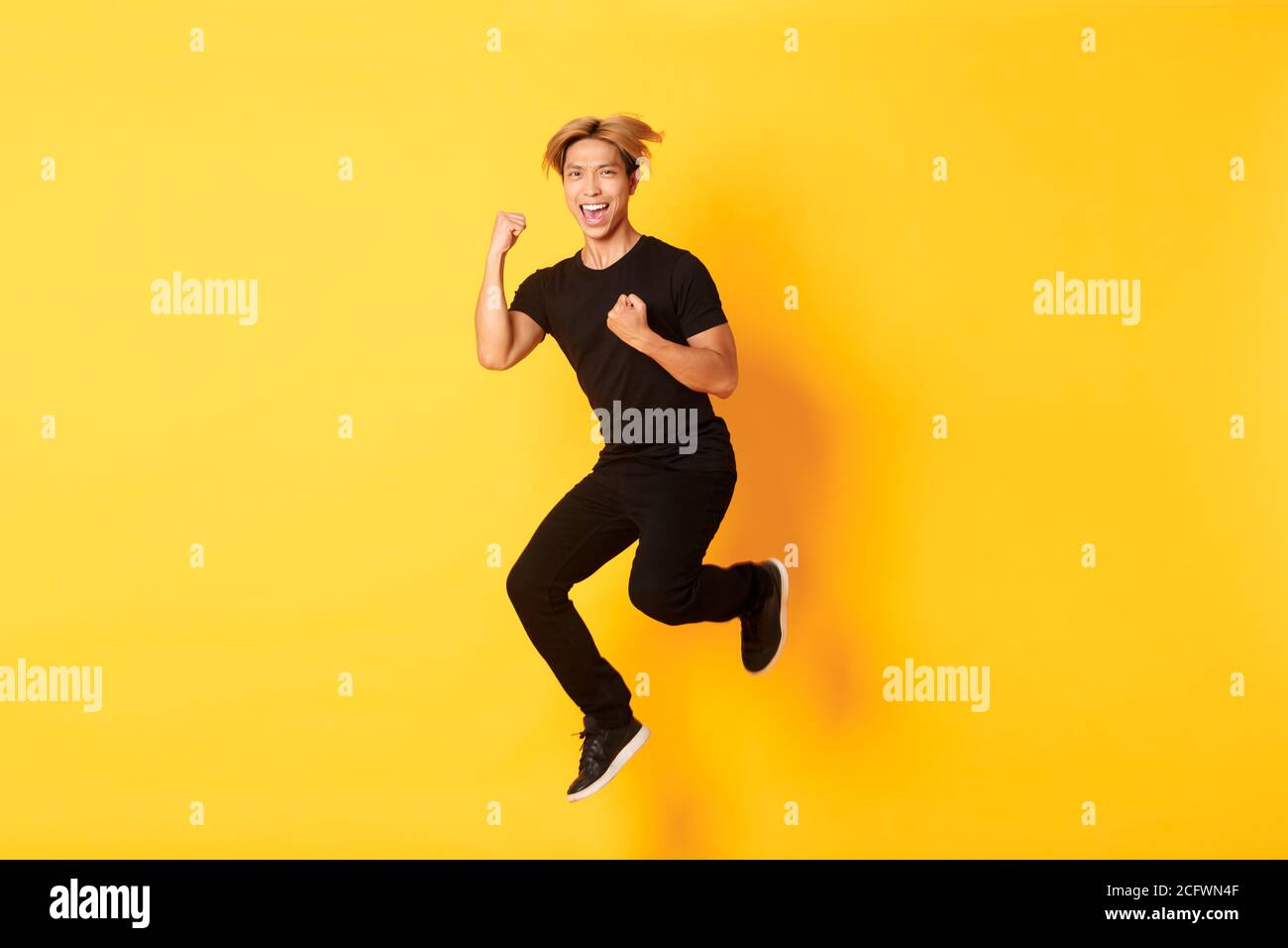 Full-length of happy attractive asian guy in black clothes jumping and ...