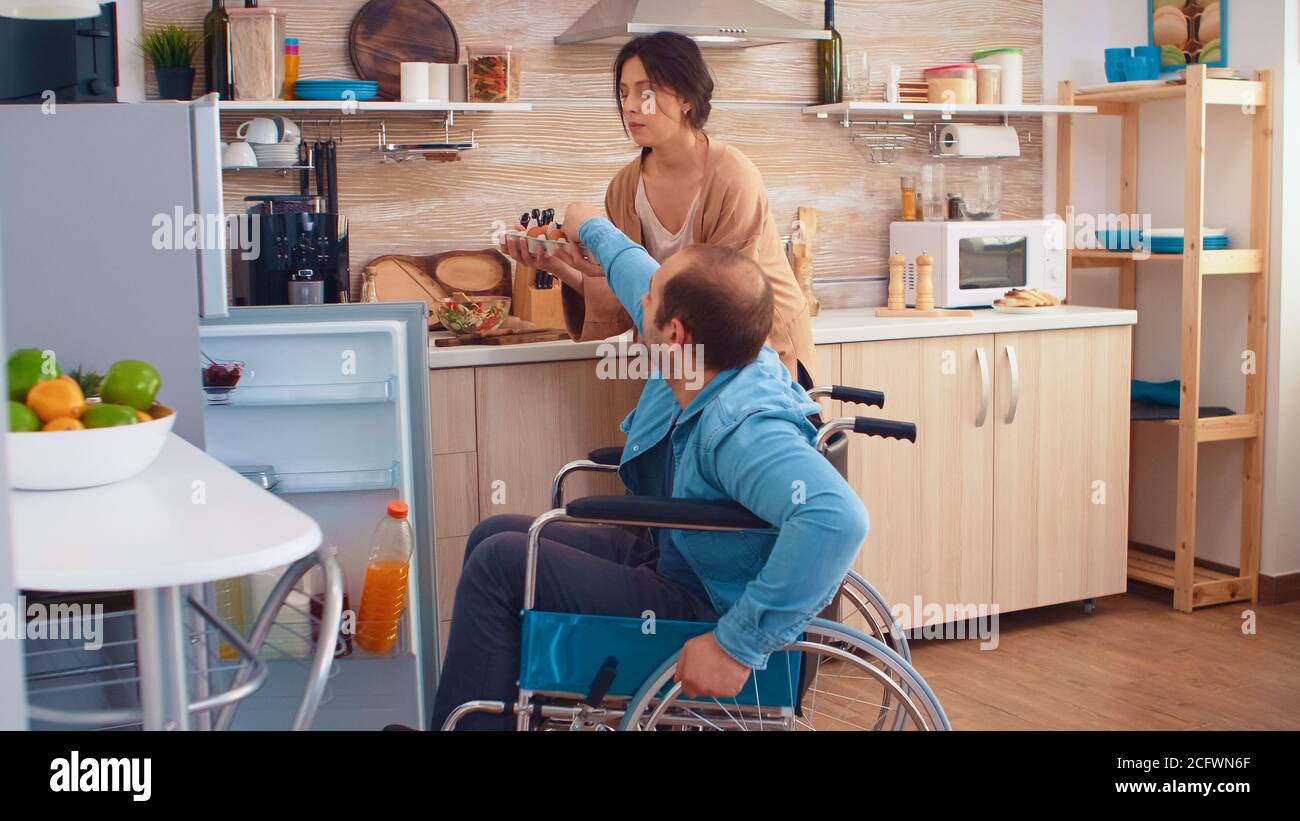 Woman helping man in wheelchair cook hi-res stock photography and images - Alamy