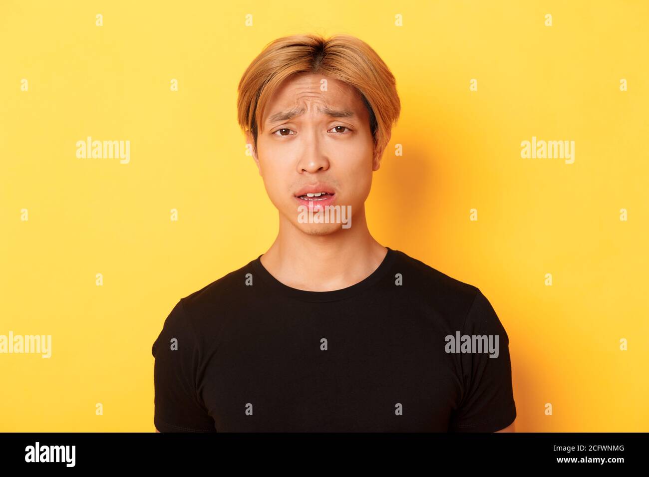 Close-up of confused and upset asian blond guy looking puzzled, open ...