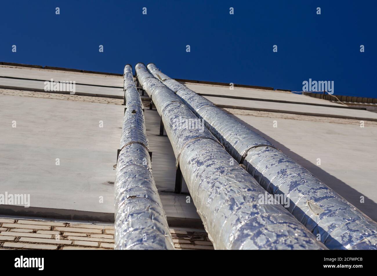 The outer wall of the building with insulated pipes. High brick wall ...