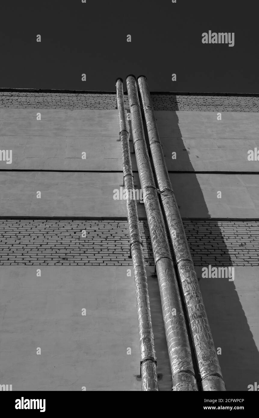 The outer wall of the building with insulated pipes. High brick wall ...