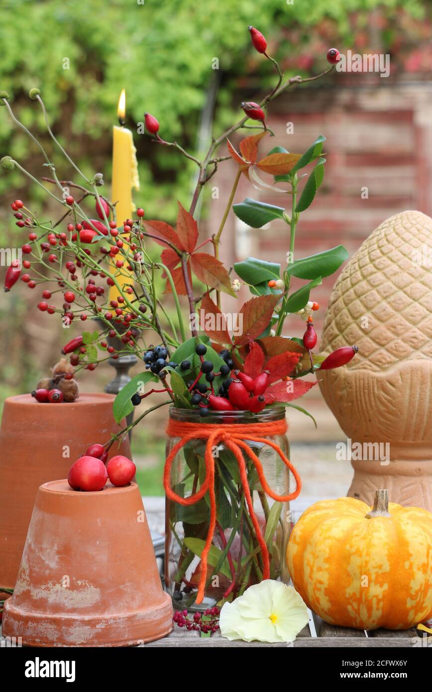 autumn decoration with branches in glass, terracotta pots and pumpkins ...