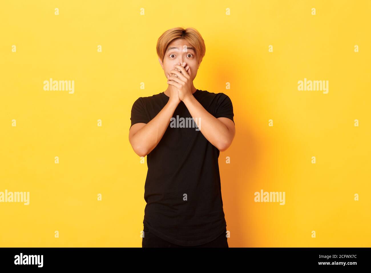 Portrait of surprised gasping asian guy with blond haircut, cover mouth ...