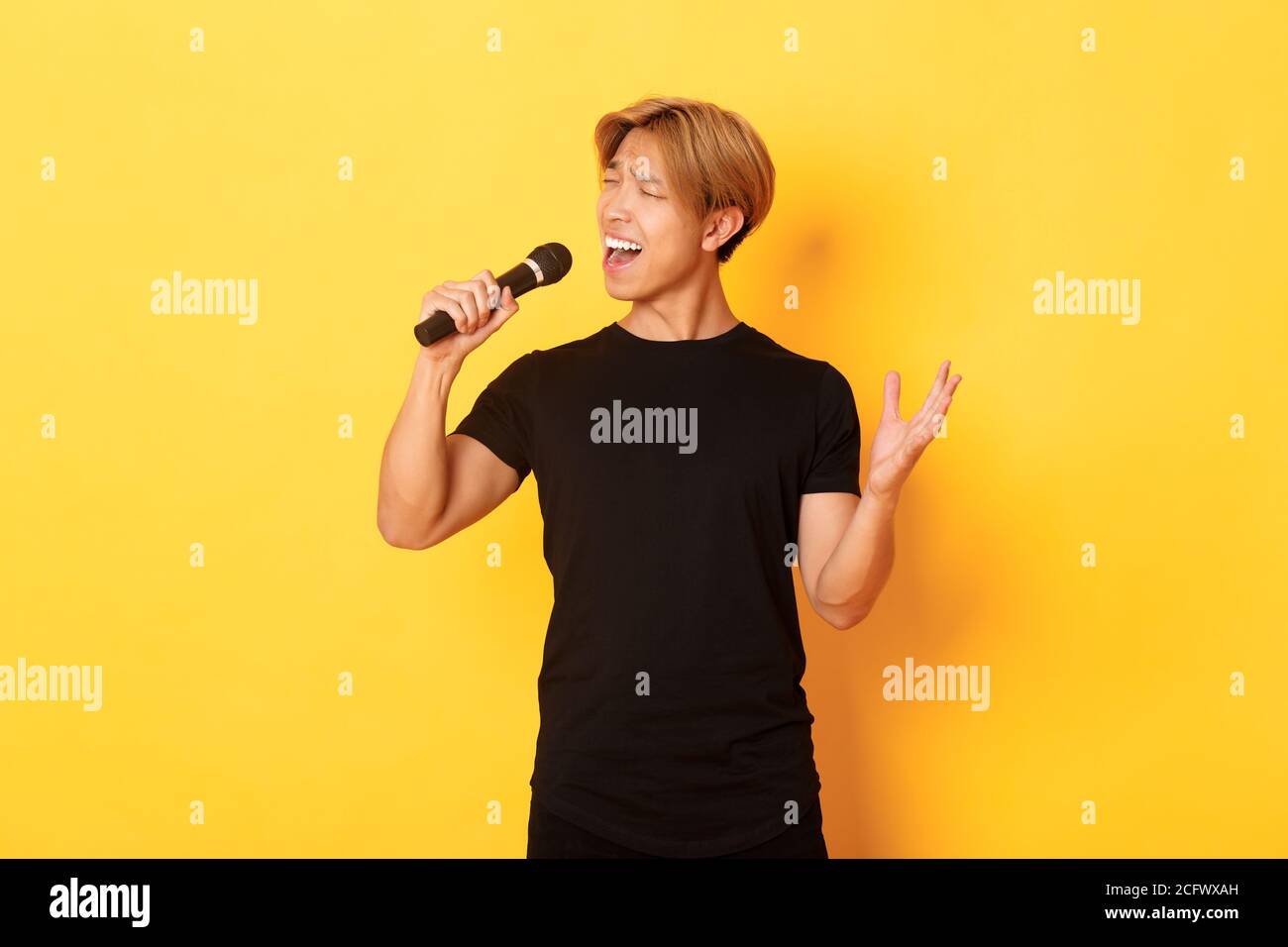 Carefree handsome asian guy, korean singer singing into microphone with ...