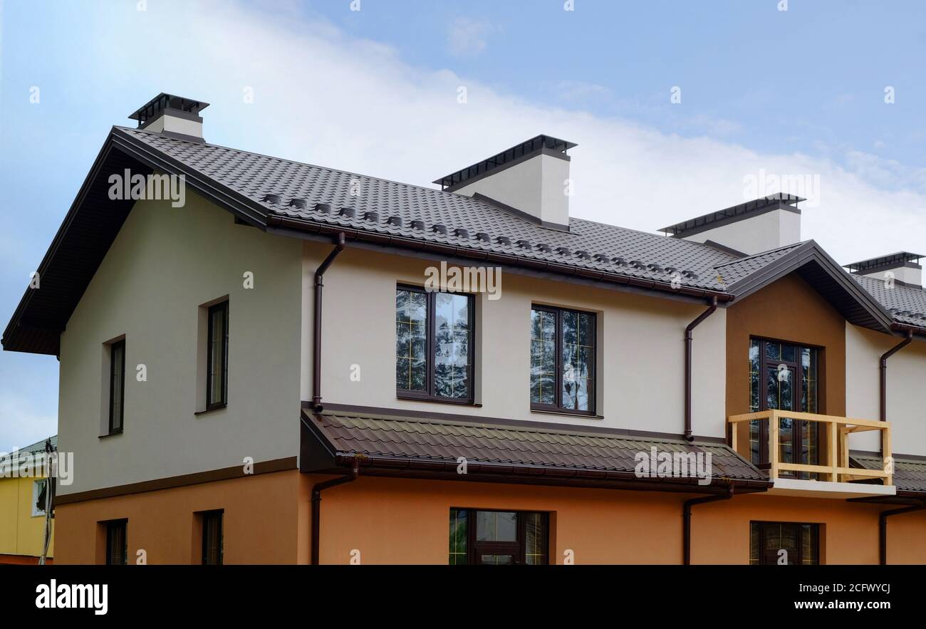 New cottage house with metal roof, rain gutter and balcony. Chimney and ...