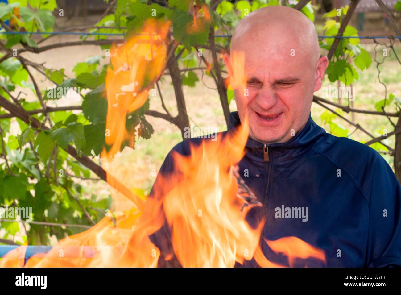 middle-aged bald man looks at the fire burning in front of him Stock ...