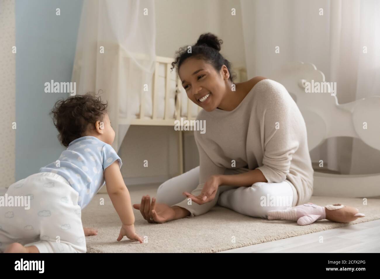 Adorable happy mixed race baby creeping to mum Stock Photo - Alamy