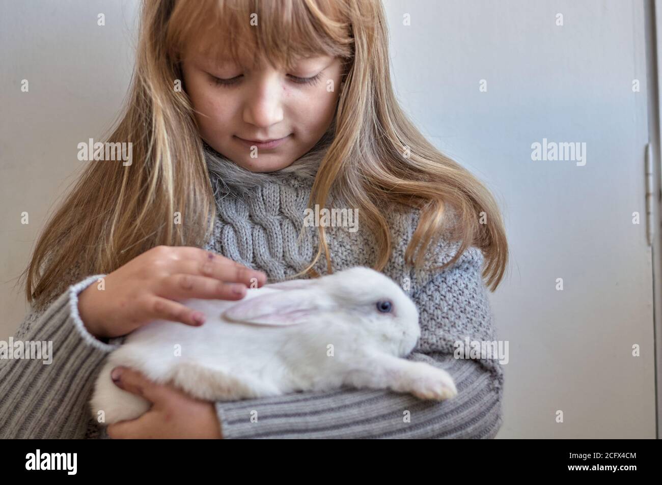 blonde girl with a white rabbit in her arms Stock Photo - Alamy