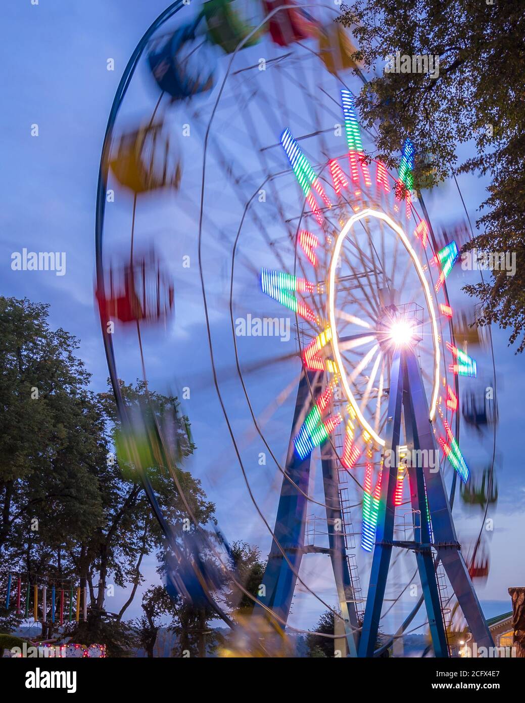 Rotating Ferris wheel in a night park with neon lighting against the ...
