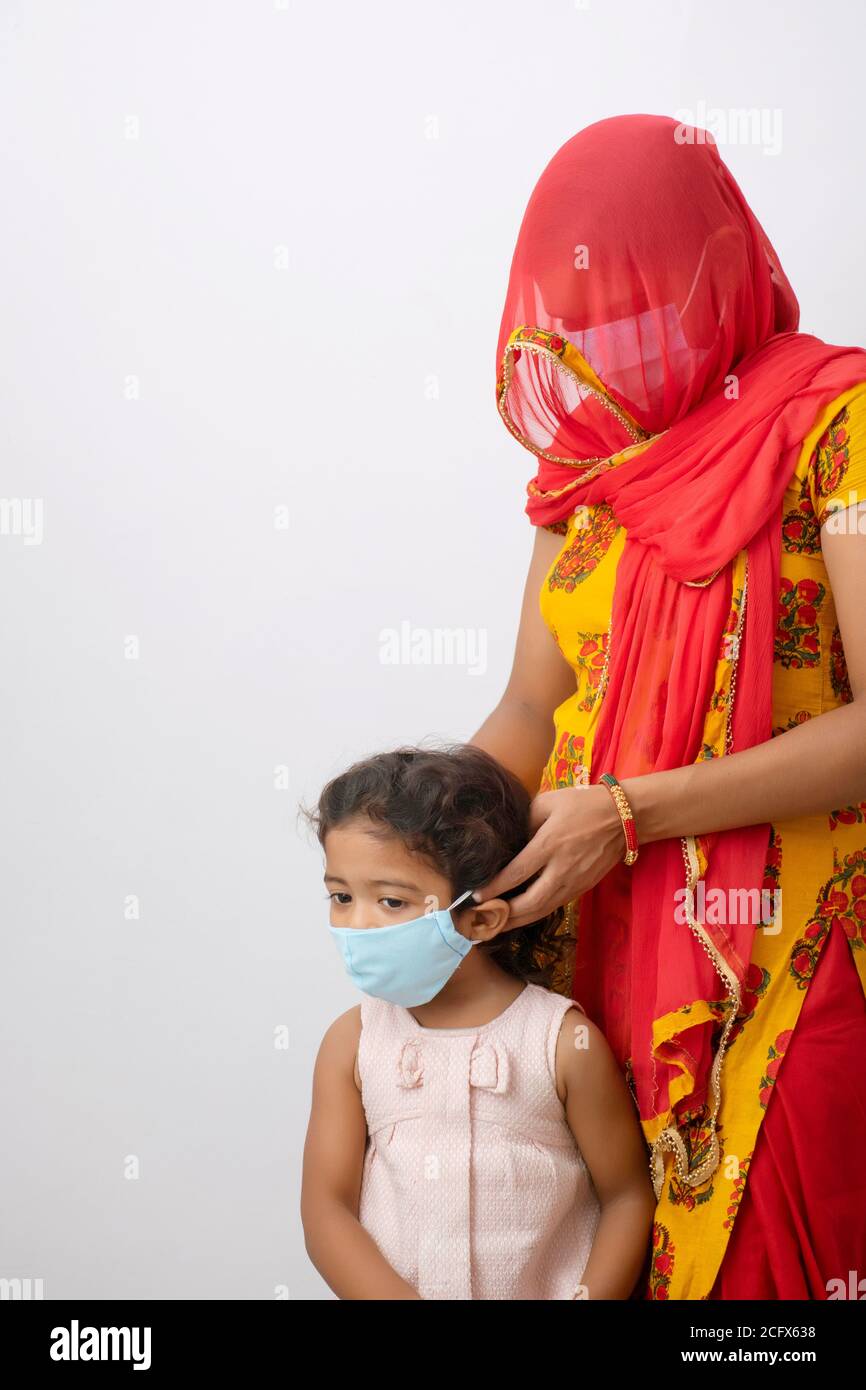 mother tying mask to a little girl's face. Close-up view of little girl ...