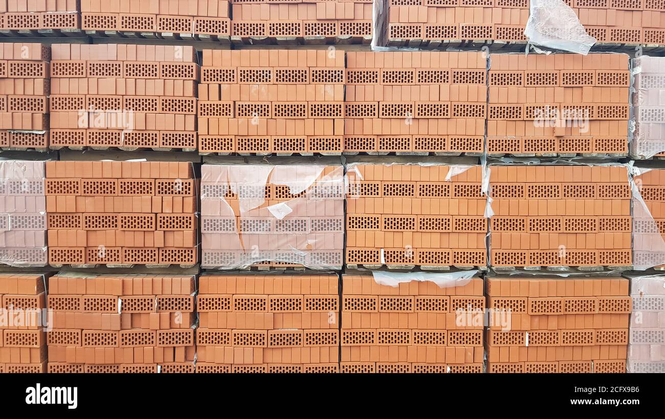 Red perforated bricks with rectangular holes on wooden pallets in an ...