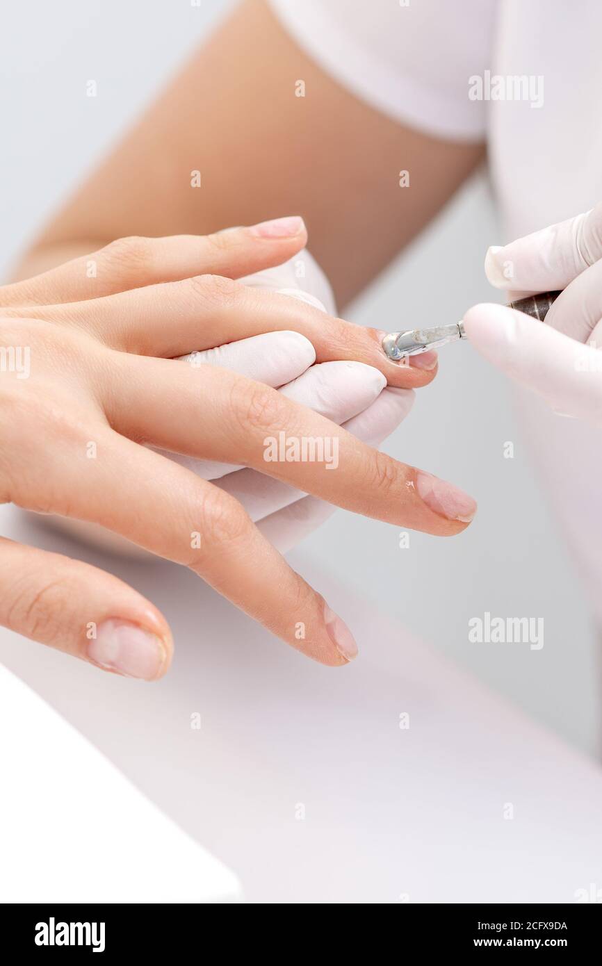 Hands of manicurist pushing cuticles on female's nails with manicure ...