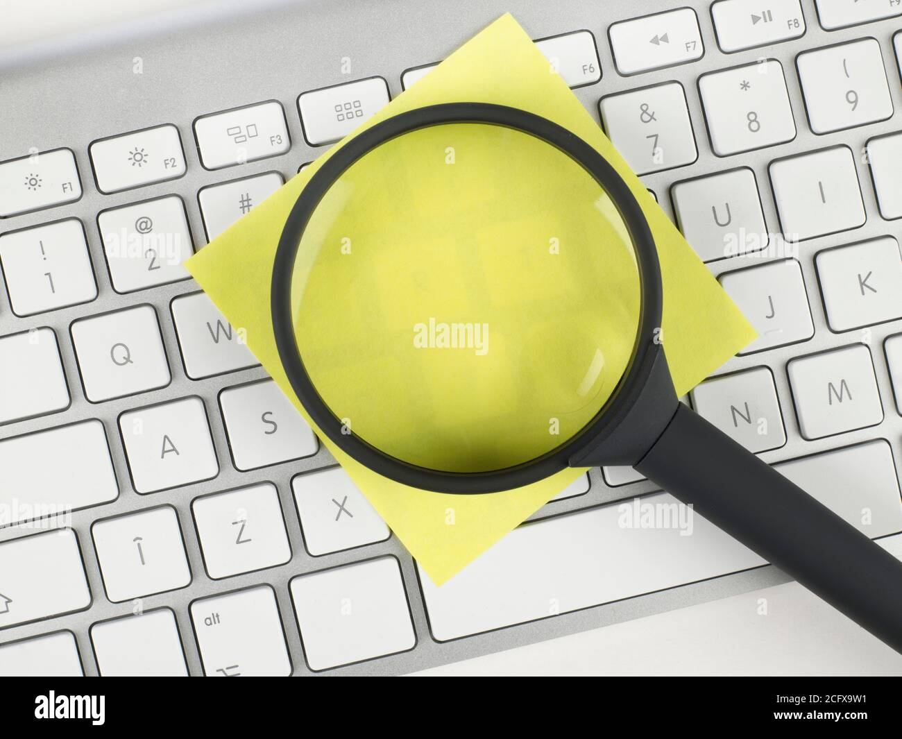 Magnifying glass and adhesive note over a keyboard Stock Photo - Alamy
