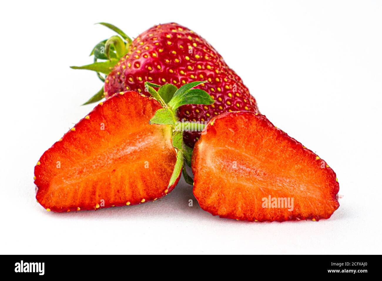 two strawberries on a white background one strawberry whole the other ...