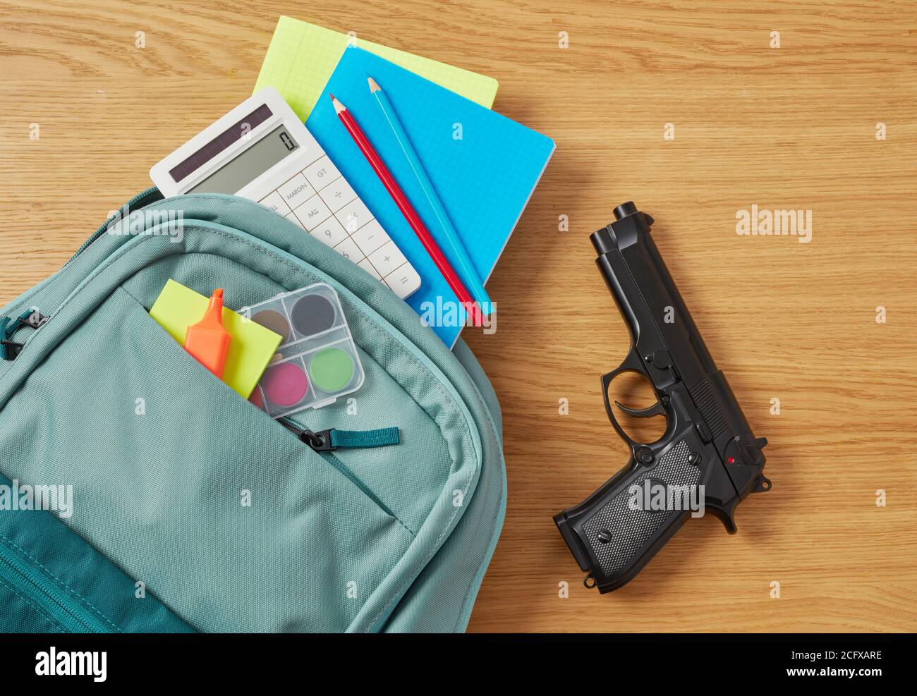 Backpack, school supplies and gun on desk Stock Photo - Alamy