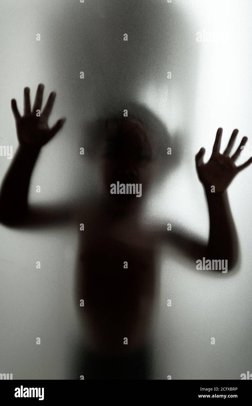 Ghost concept shadow of a child behind the matte glass blurry hand and ...