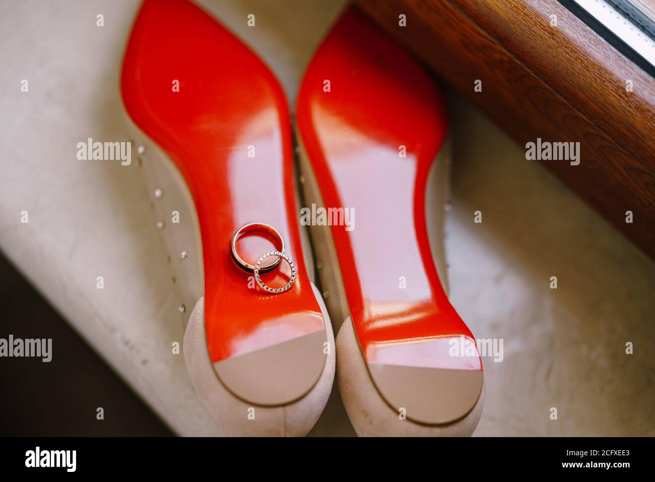 Wedding gold rings on the red sole of ballet shoes for the bride on the ...