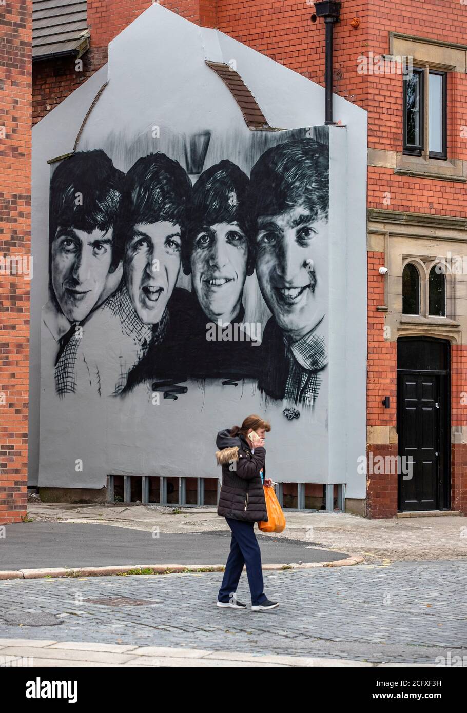A woman walks past a new Beatles mural on the gable end of The Pheonix ...