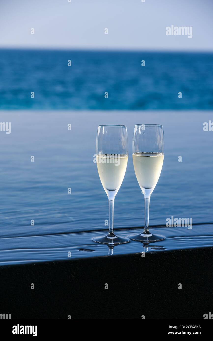 A pair of champagne flutes are set out on the edge of an infinity pool ...
