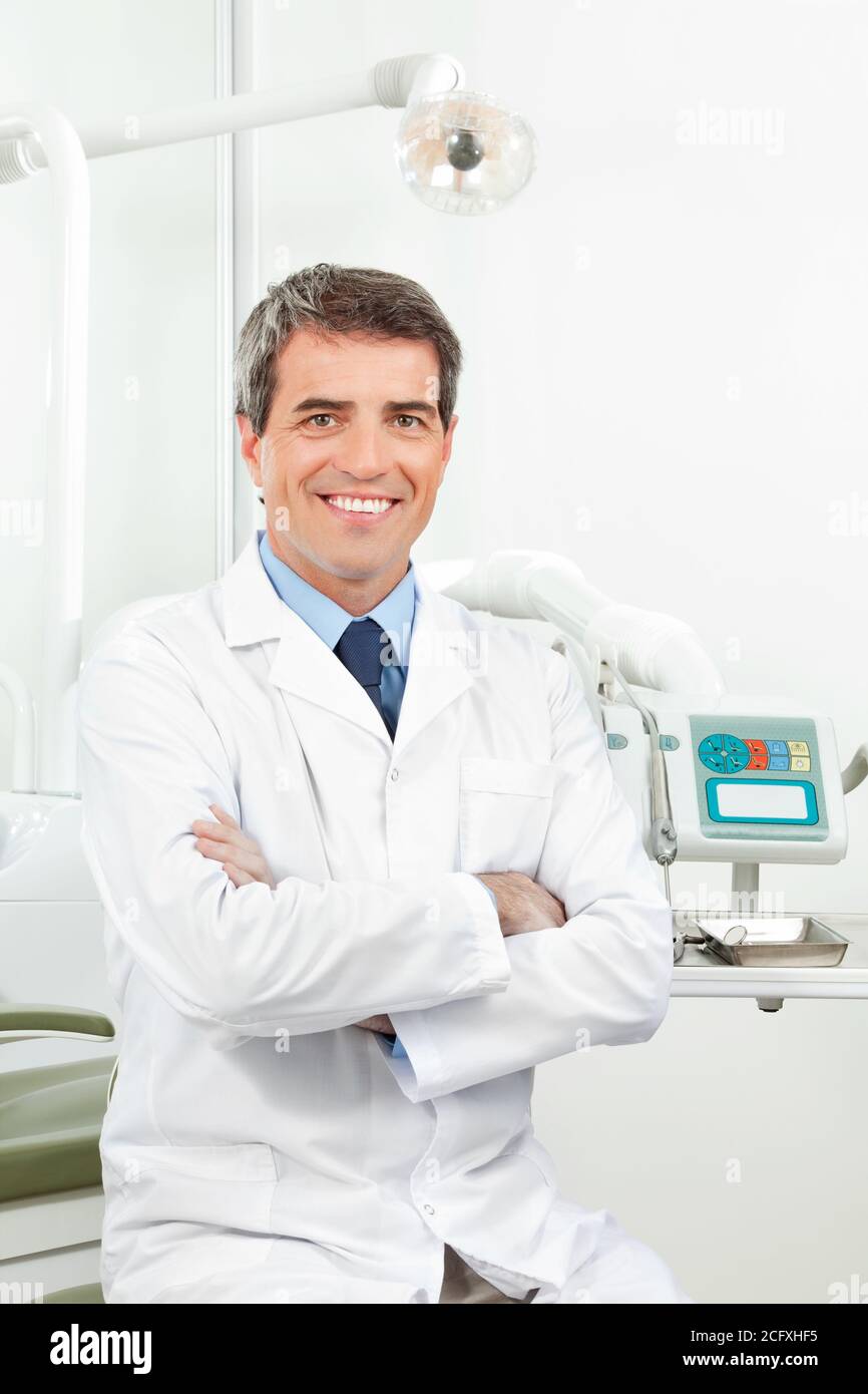 Happy dentist with crossed arms in his practice Stock Photo - Alamy