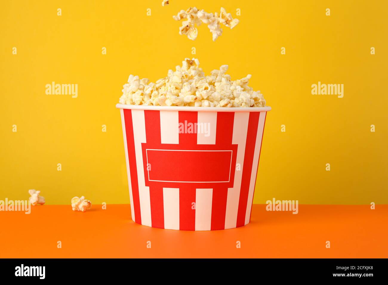 Cardboard bucket with tasty popcorn against yellow background Stock ...