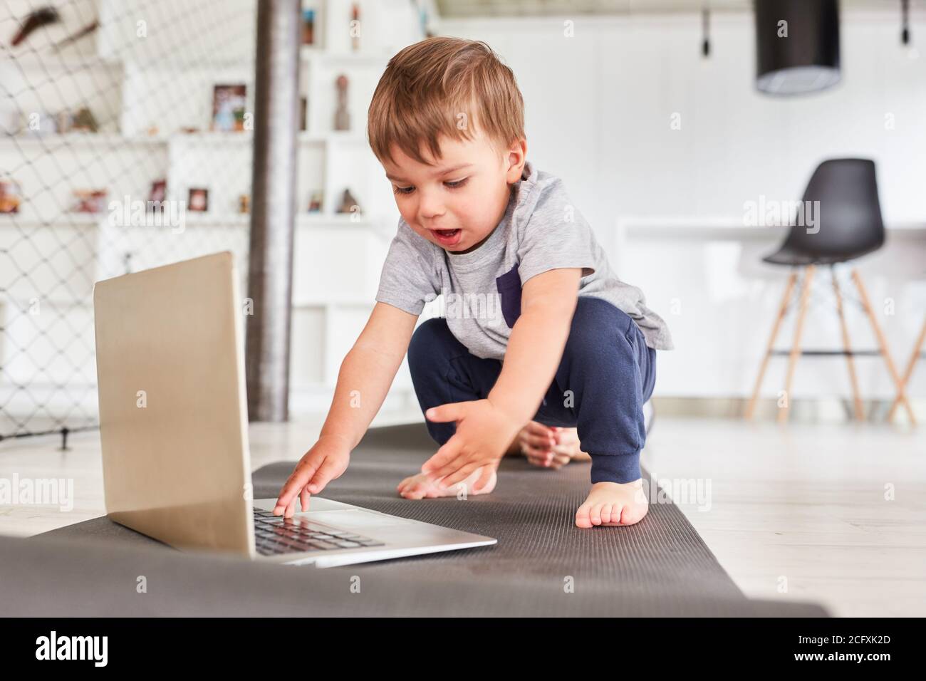 Little boy playing with a laptop computer in the living room on the floor Stock Photo - Alamy
