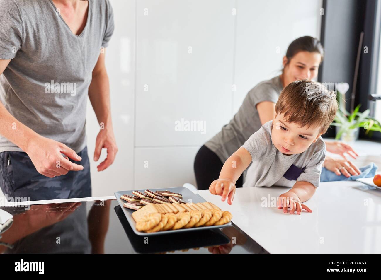 Little child hungrily reaches for cookies in the kitchen with hand ...