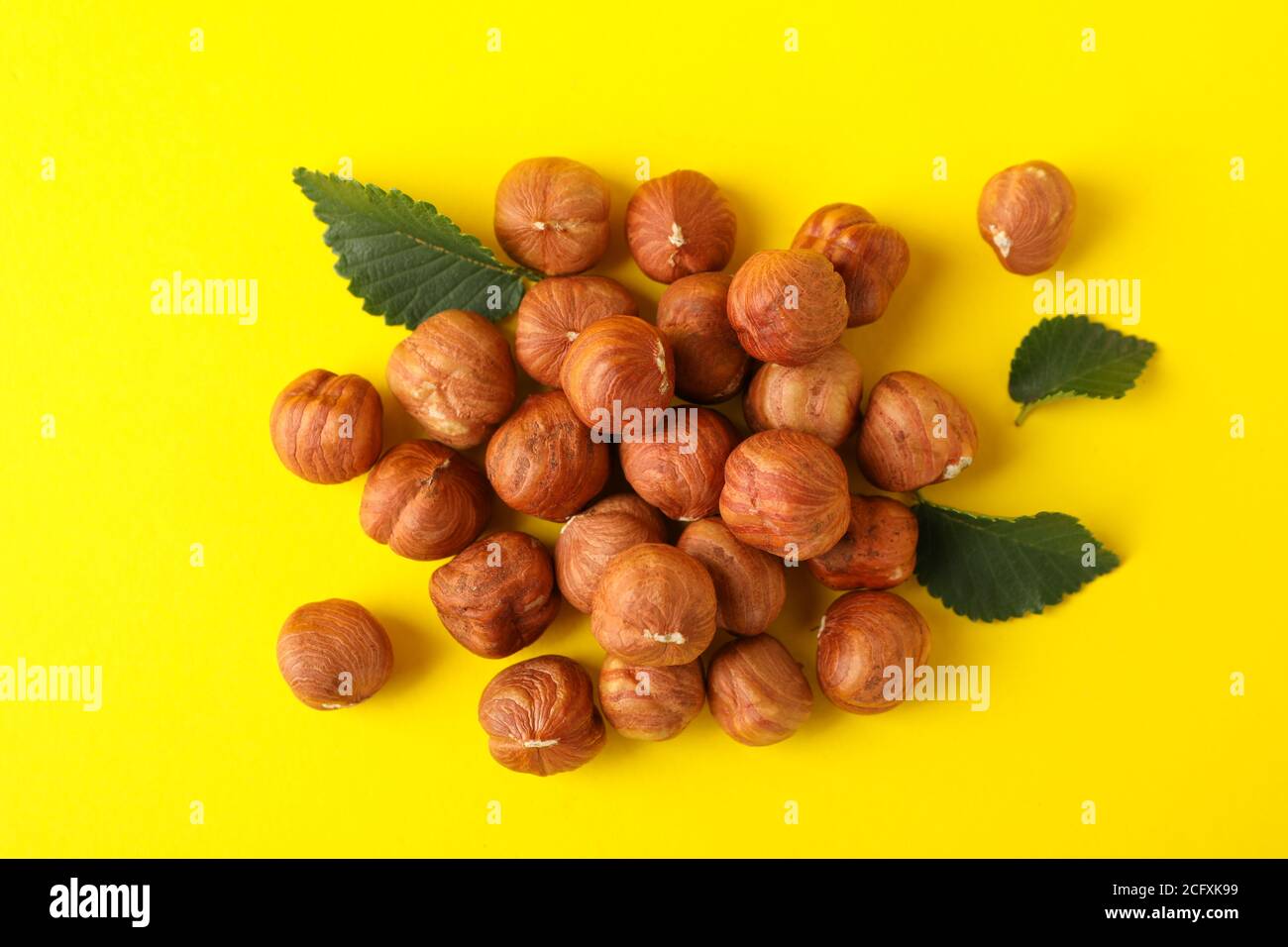 Tasty hazelnuts and leaves on yellow background. Vitamin food Stock ...