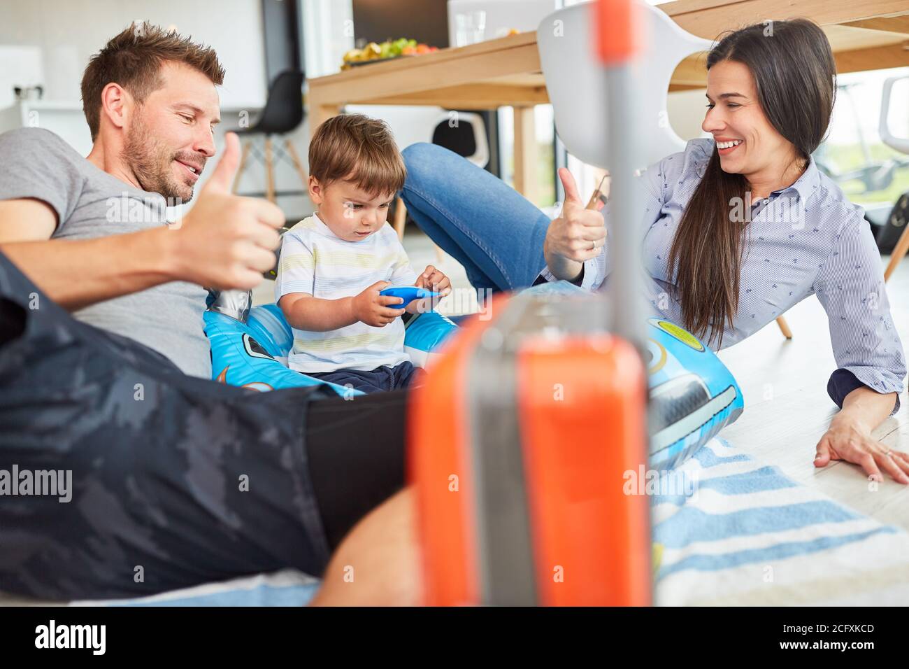 Happy family with thumbs up playing in racing car together with child ...