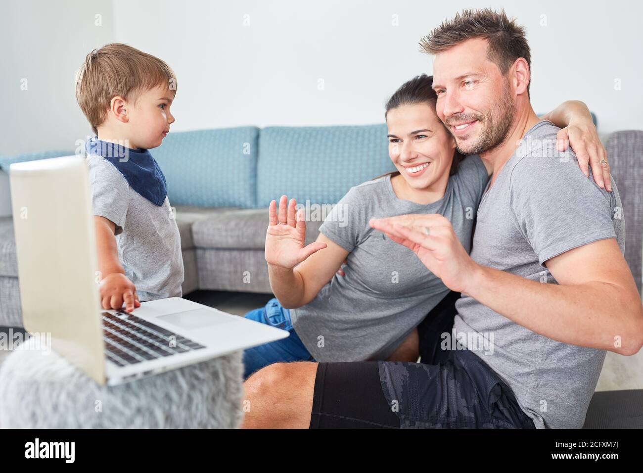 Parents waving happily in front of the laptop computer while streaming ...