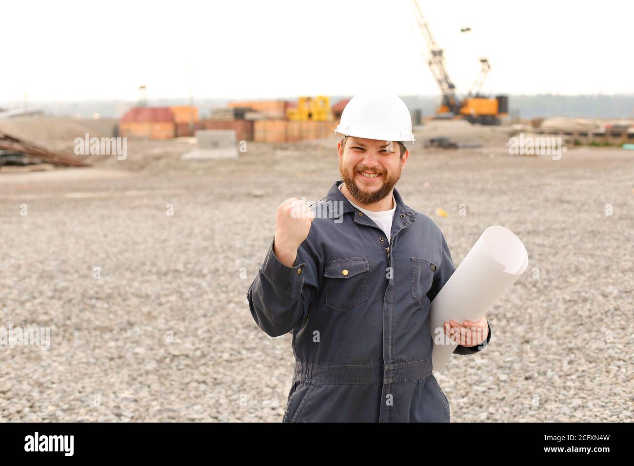 Happy foreman holding blueprints papers on construction site Stock ...