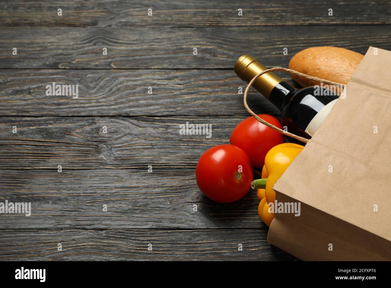 Paper bag with different food on wooden background, space for text ...