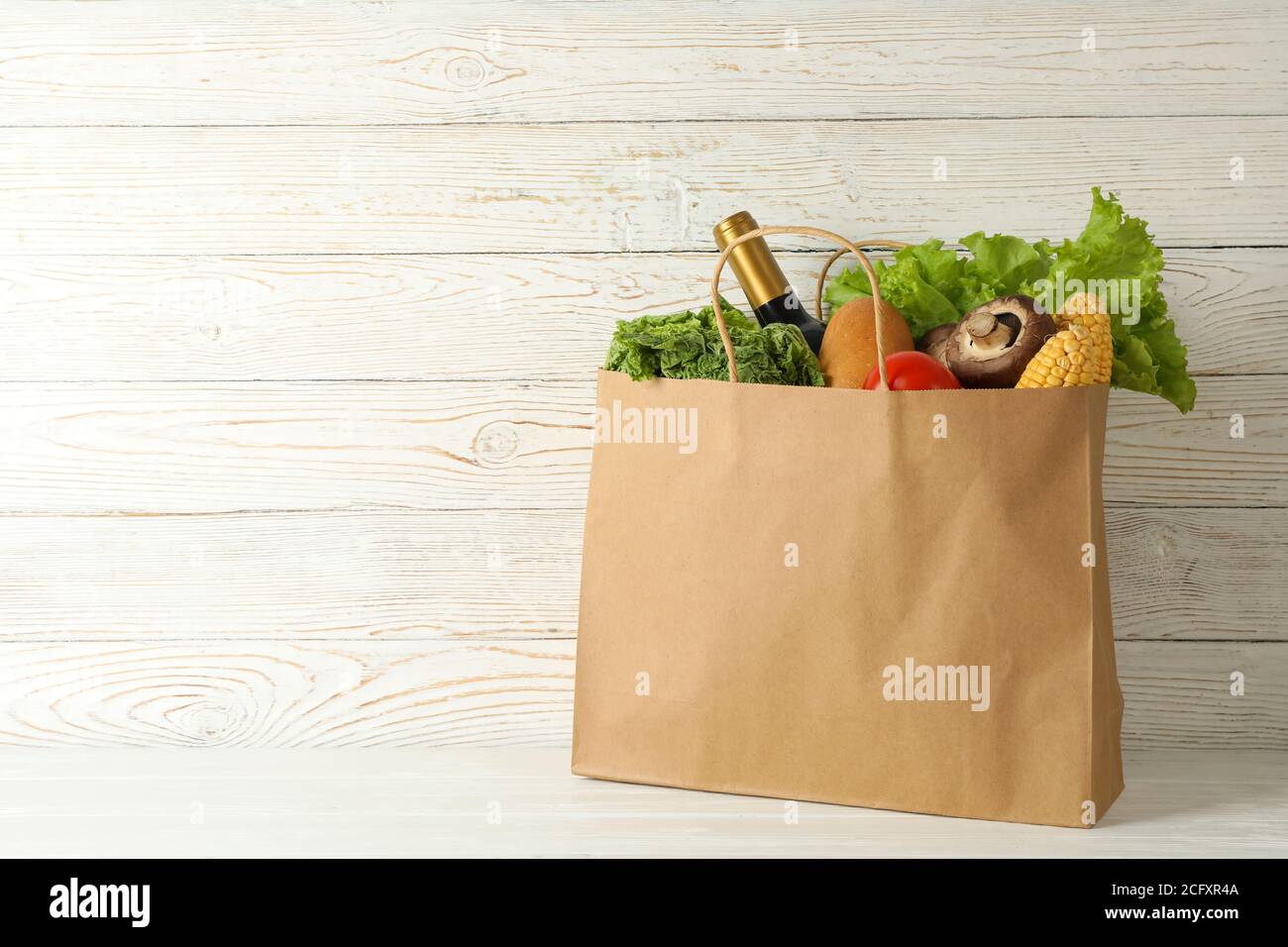 Paper bag with different food on white wooden background Stock Photo ...