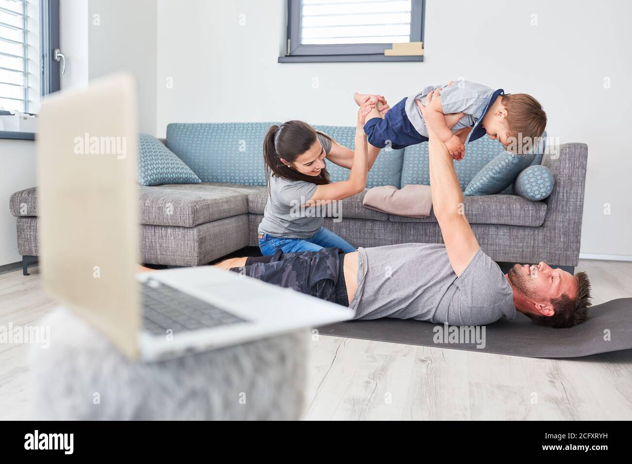 Parents romp and play with their son in the living room while streaming ...