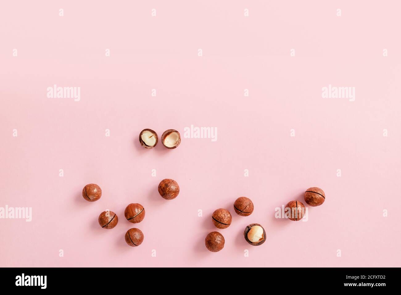 Cracked macadamia nuts on pink background with copy space Stock Photo ...
