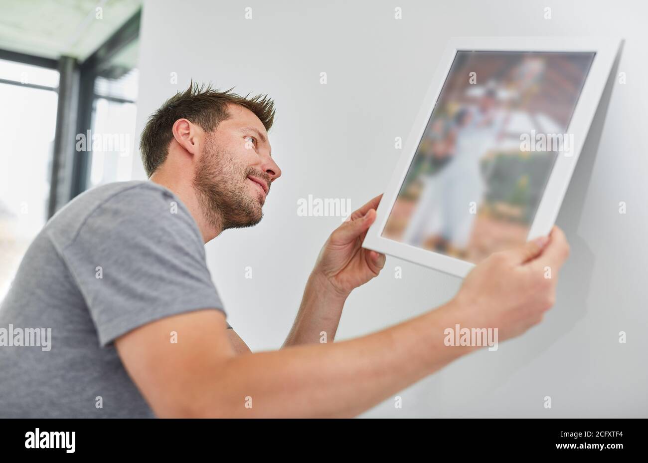 Man working as a handyman when hanging a picture or picture frame in ...