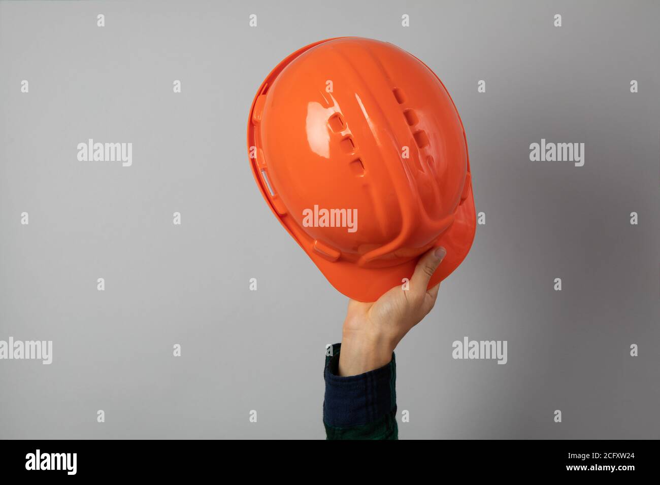 Hand hold safety helmet on gray background Stock Photo - Alamy