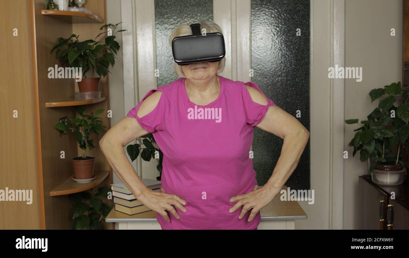 Senior grandmother in virtual headset glasses watching 3D video in VR ...
