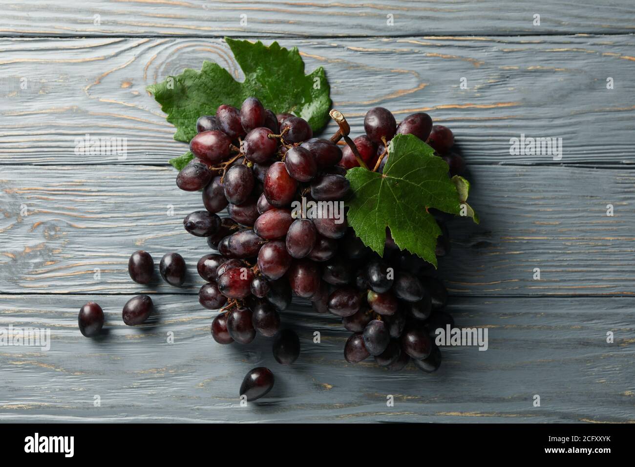 Fresh ripe grape with leaves on gray wooden background Stock Photo - Alamy