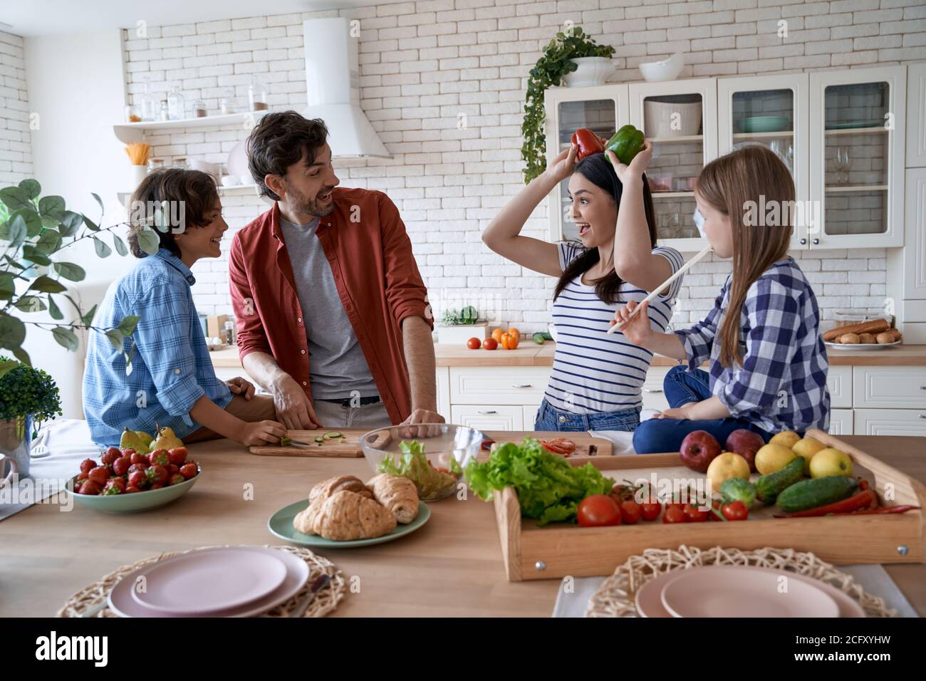 Lovely family with kids having fun while cooking together in kitchen at ...