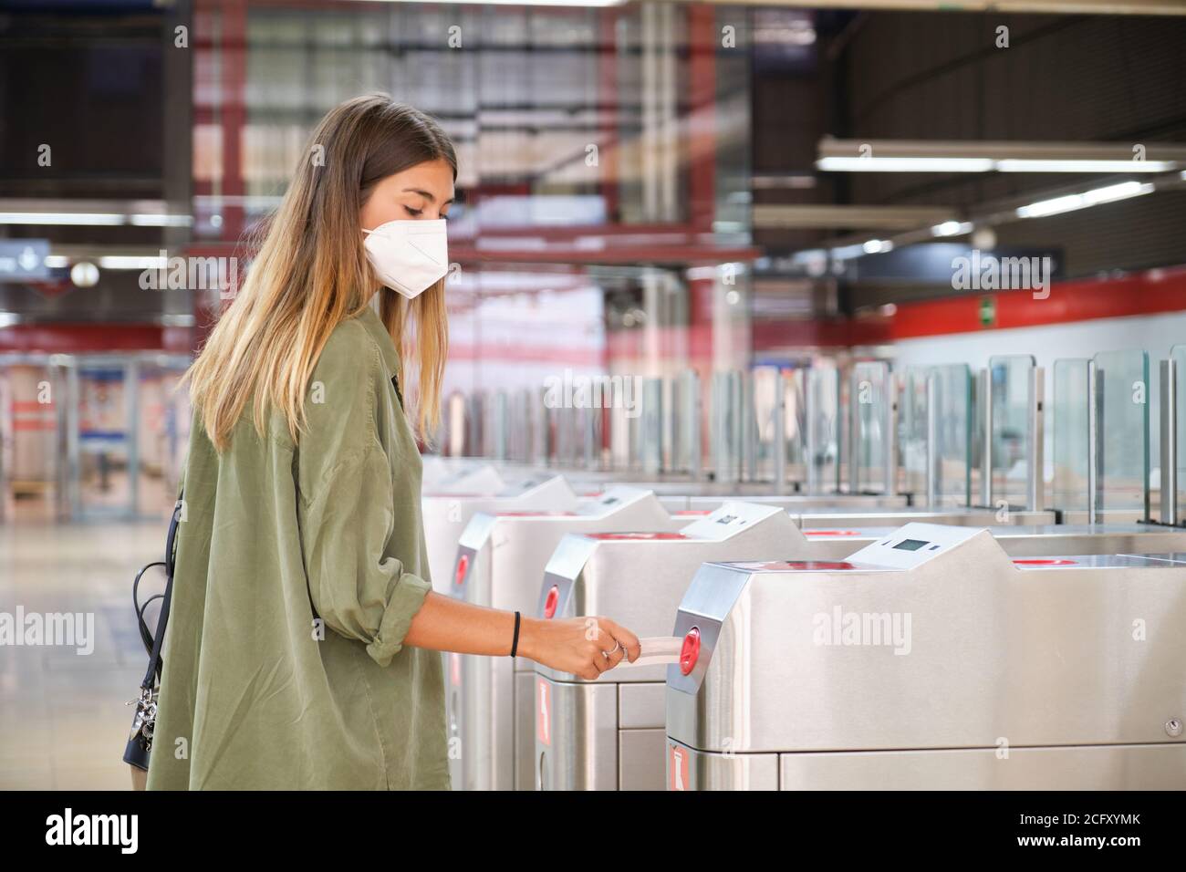 Young woman wearing face mask, entering through the train station ...