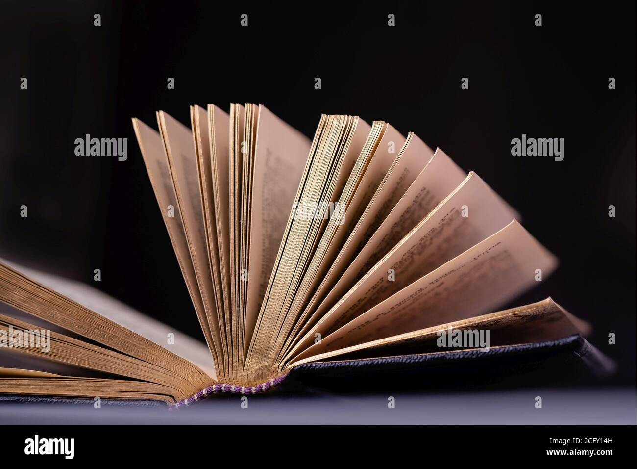 Opened old book with gold pages on a black background Stock Photo - Alamy