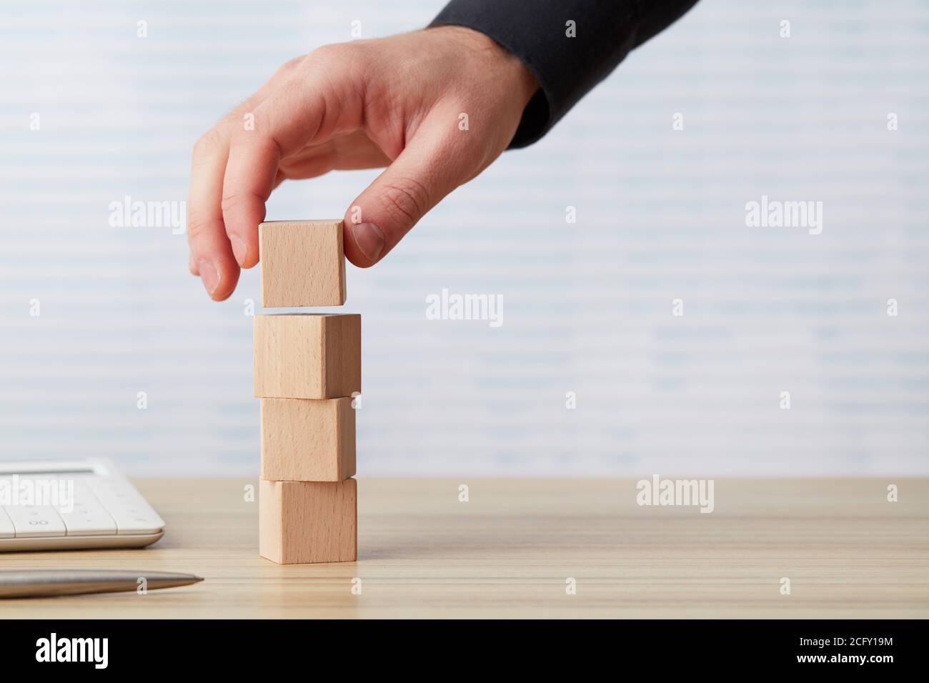 Hand arranging wooden block on stack Stock Photo - Alamy