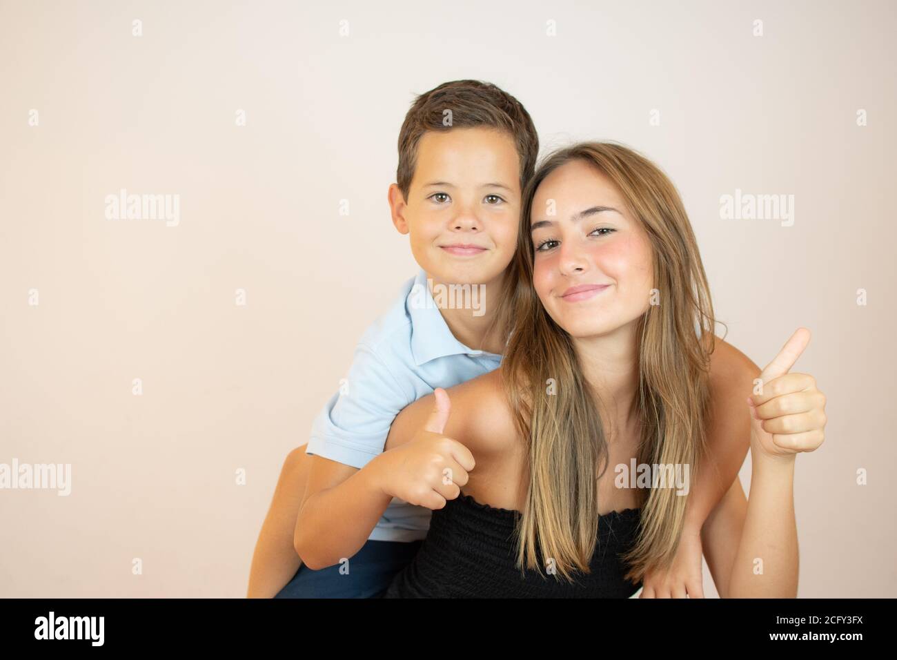 Two smiling brothers with thumbs up on white background Stock Photo - Alamy