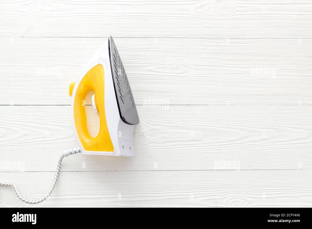 Yellow iron on ironing board. Top view, copy space Stock Photo - Alamy