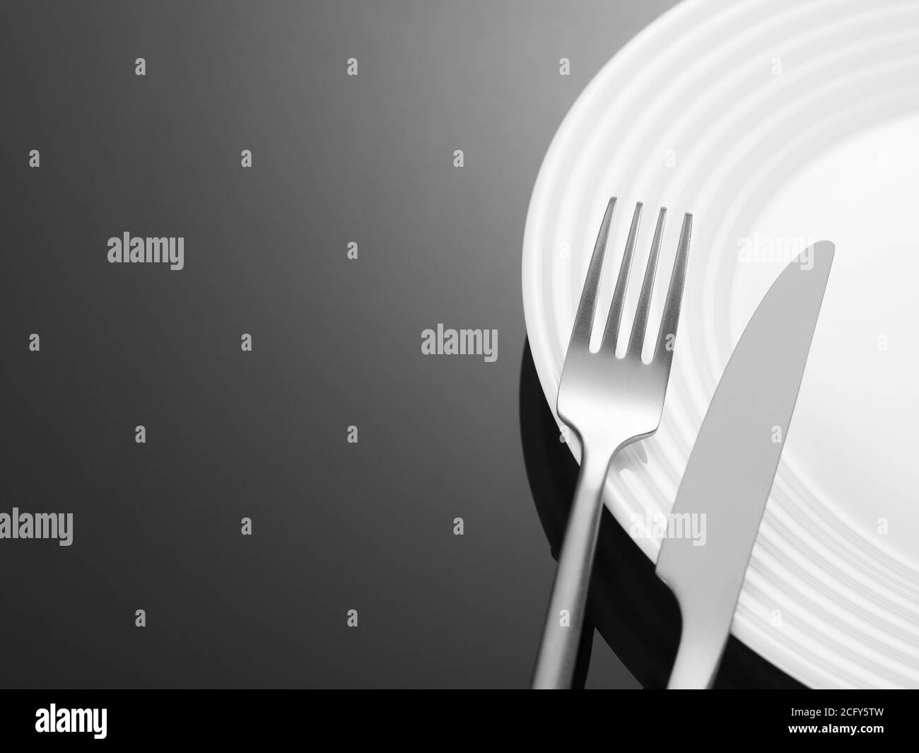 Fork, knife and plate on black background Stock Photo - Alamy