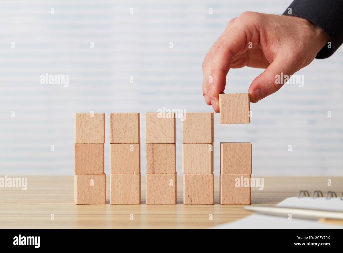 Hand arranging wooden block on desk Stock Photo - Alamy