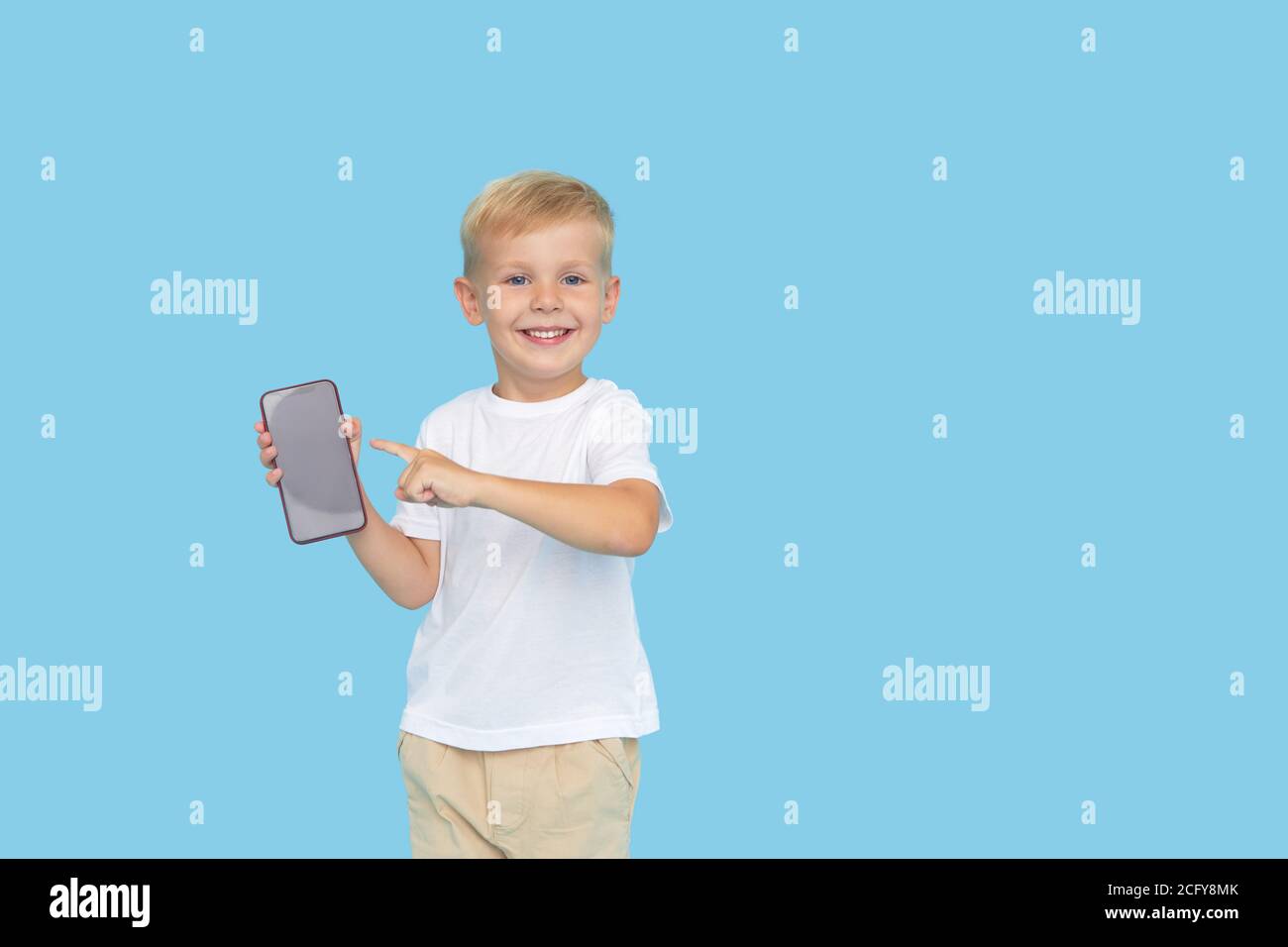 Cute smilling child boy with smartphone on blue background. Advertising ...