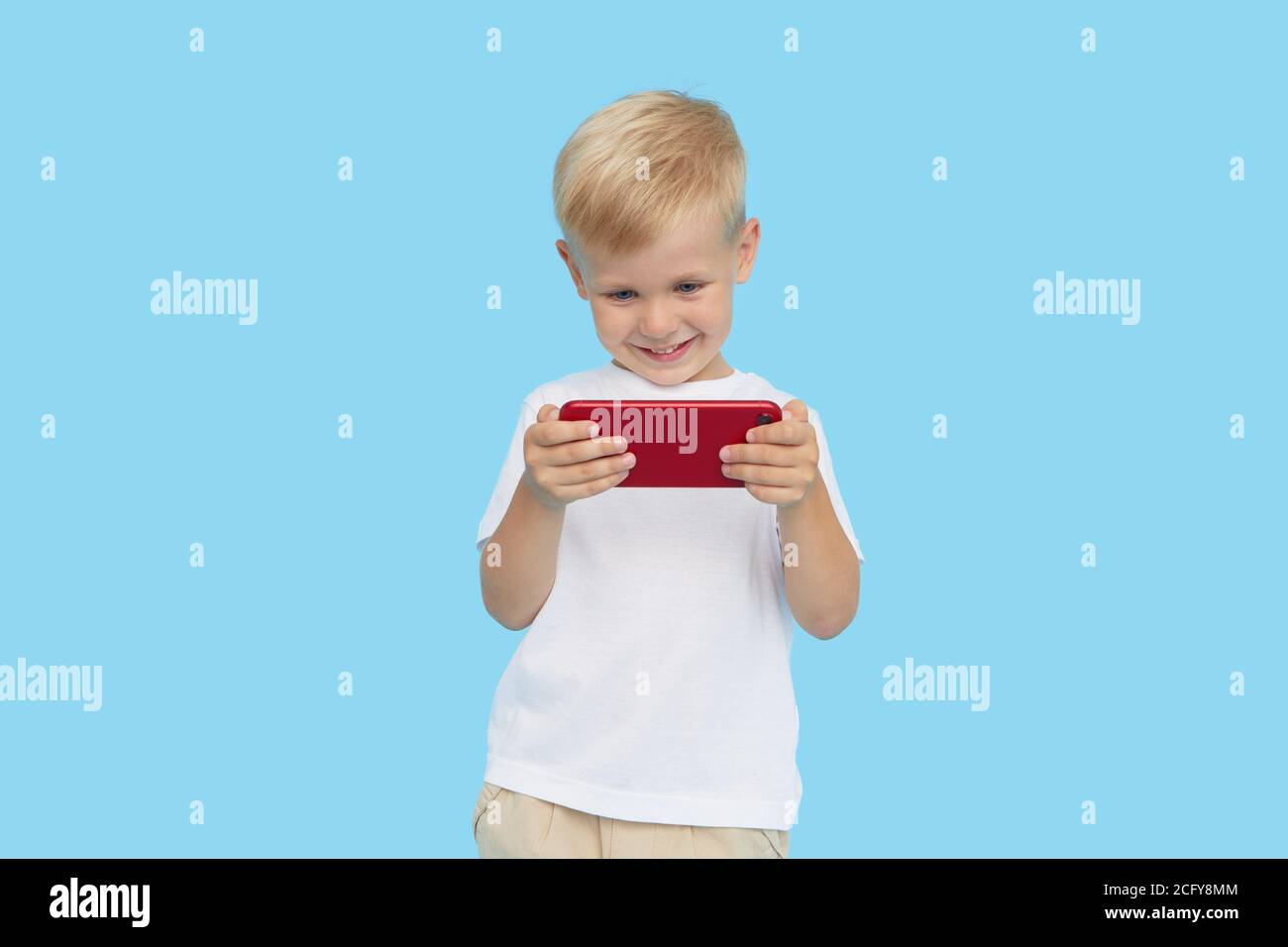 Cute smilling child boy with smartphone on blue background. Advertising ...