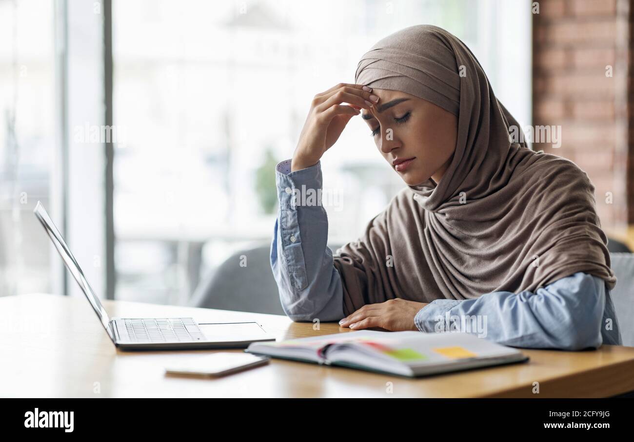 Tired muslim girl with laptop and notepad at cafe Stock Photo - Alamy